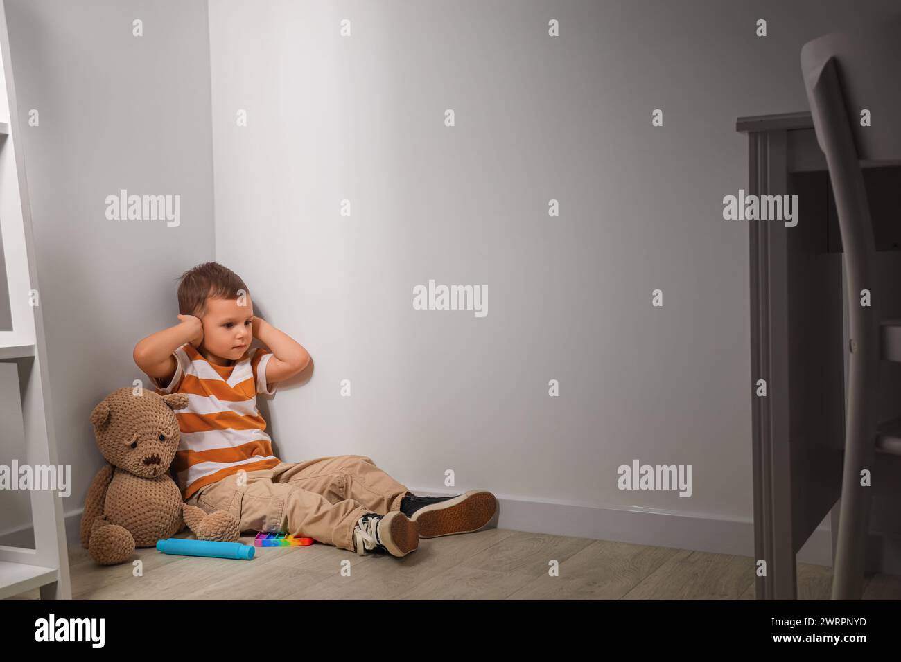 Stressed little boy with autistic disorder and toys sitting in corner ...