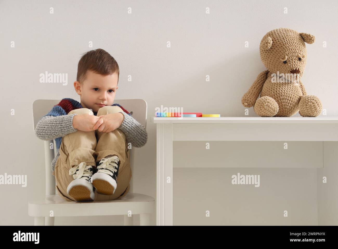 Lonely little boy with autistic disorder sitting in chair at home Stock ...