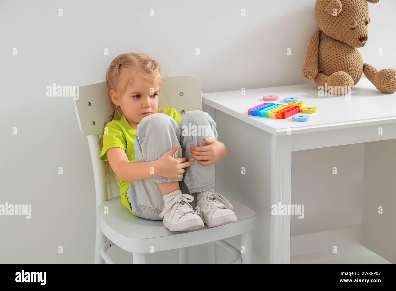 Lonely little girl with autistic disorder sitting in chair at home ...