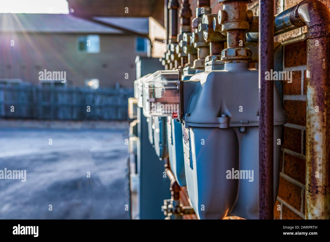 sun flare over a Row of gas utility meters on the outside wall of an ...