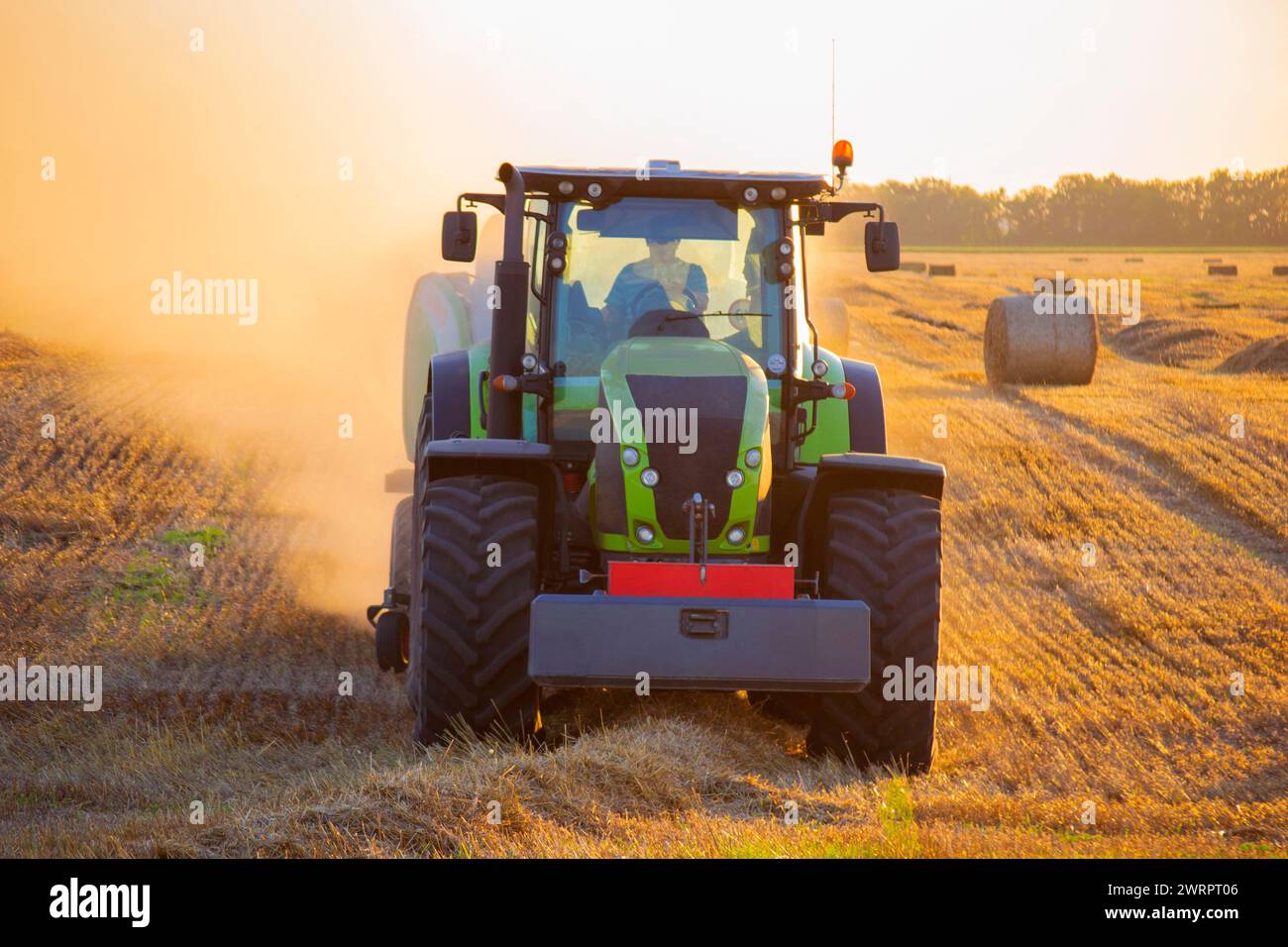 Combine harvester pressing straw from field into bales. Sunny summer ...