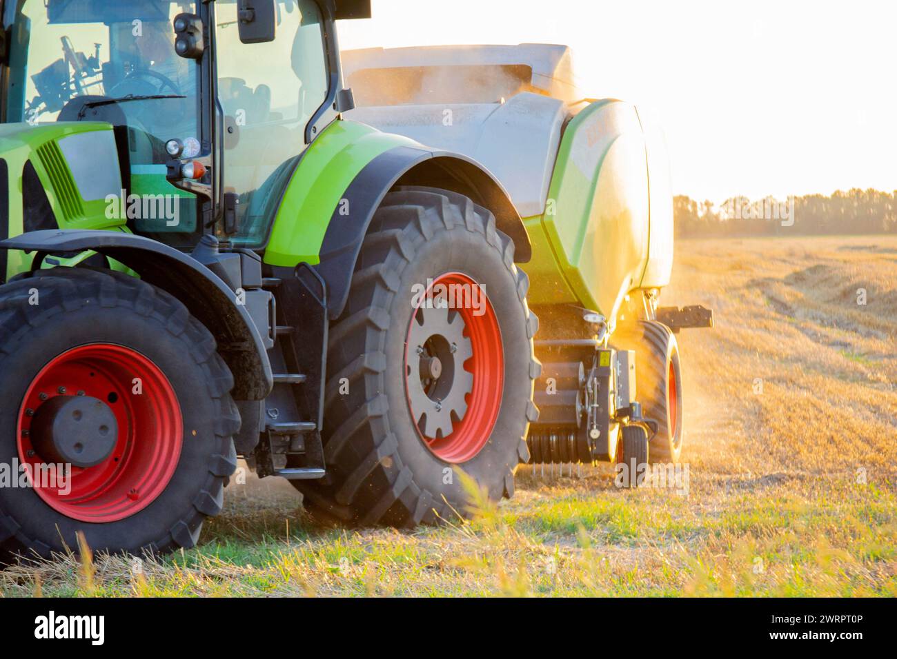 Combine harvester pressing straw from field into bales. Sunny summer ...