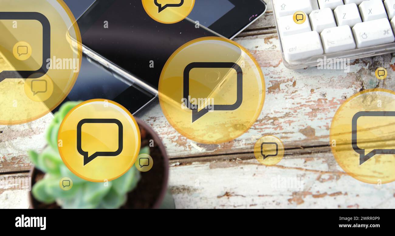 Image of yellow digital message icons flying up over electronic devices ...