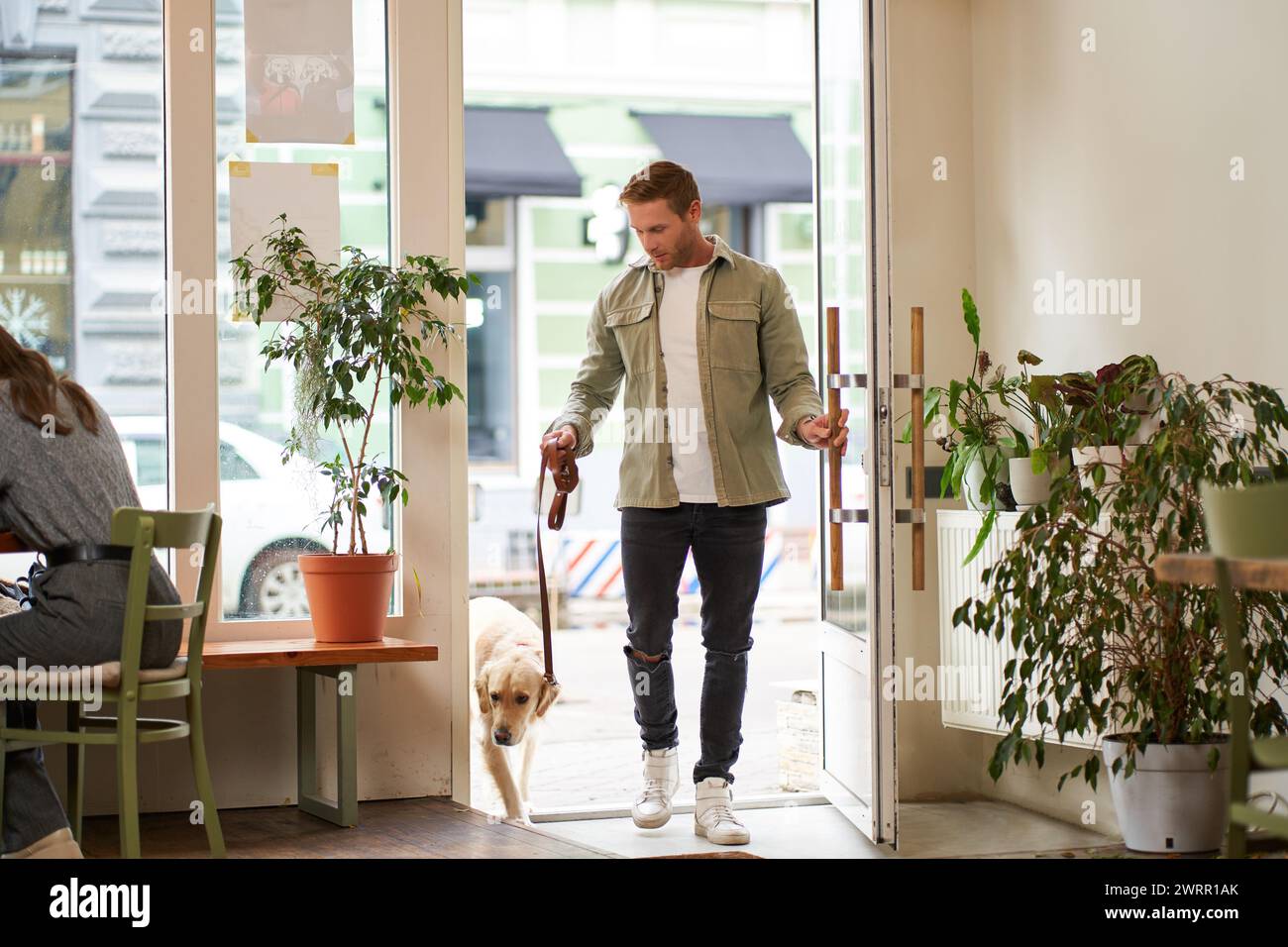 Portrait of handsome young man walks into the cafe with his dog on a ...