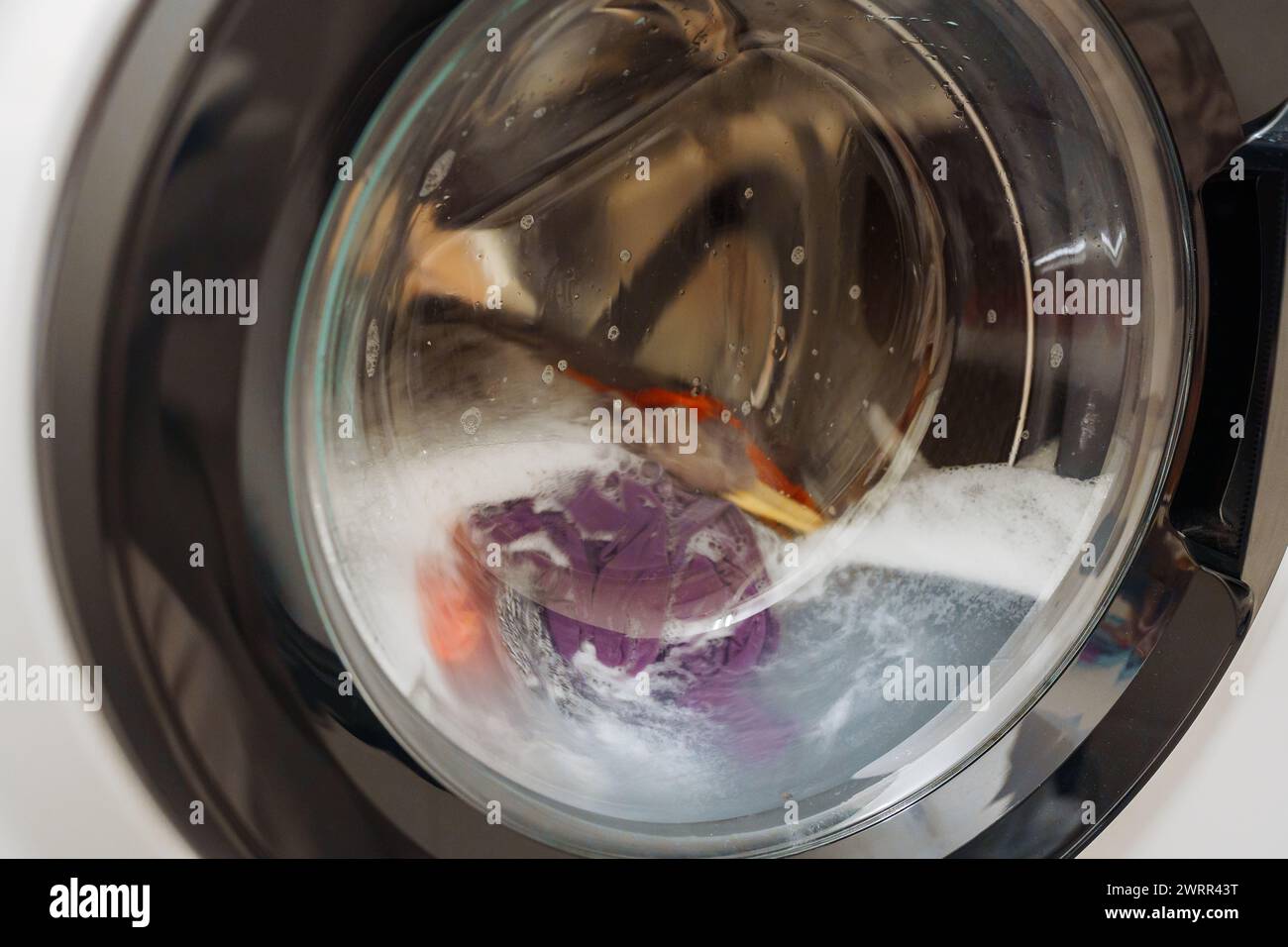 Closeup of washing machine door with spinning laundry Stock Photo - Alamy