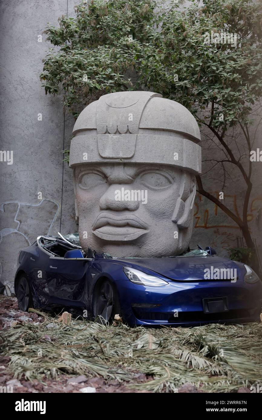 A replica of a colossal Olmec head is crushing a Tesla car in a vacant ...
