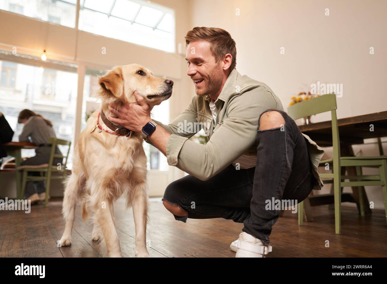 Portrait of happy young man enters coffee shop with his golden ...