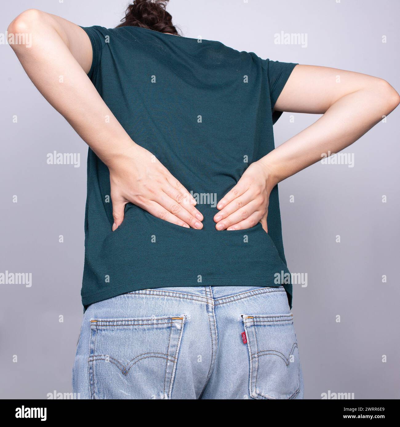 The image focuses on a person's lower back as they experience the ...