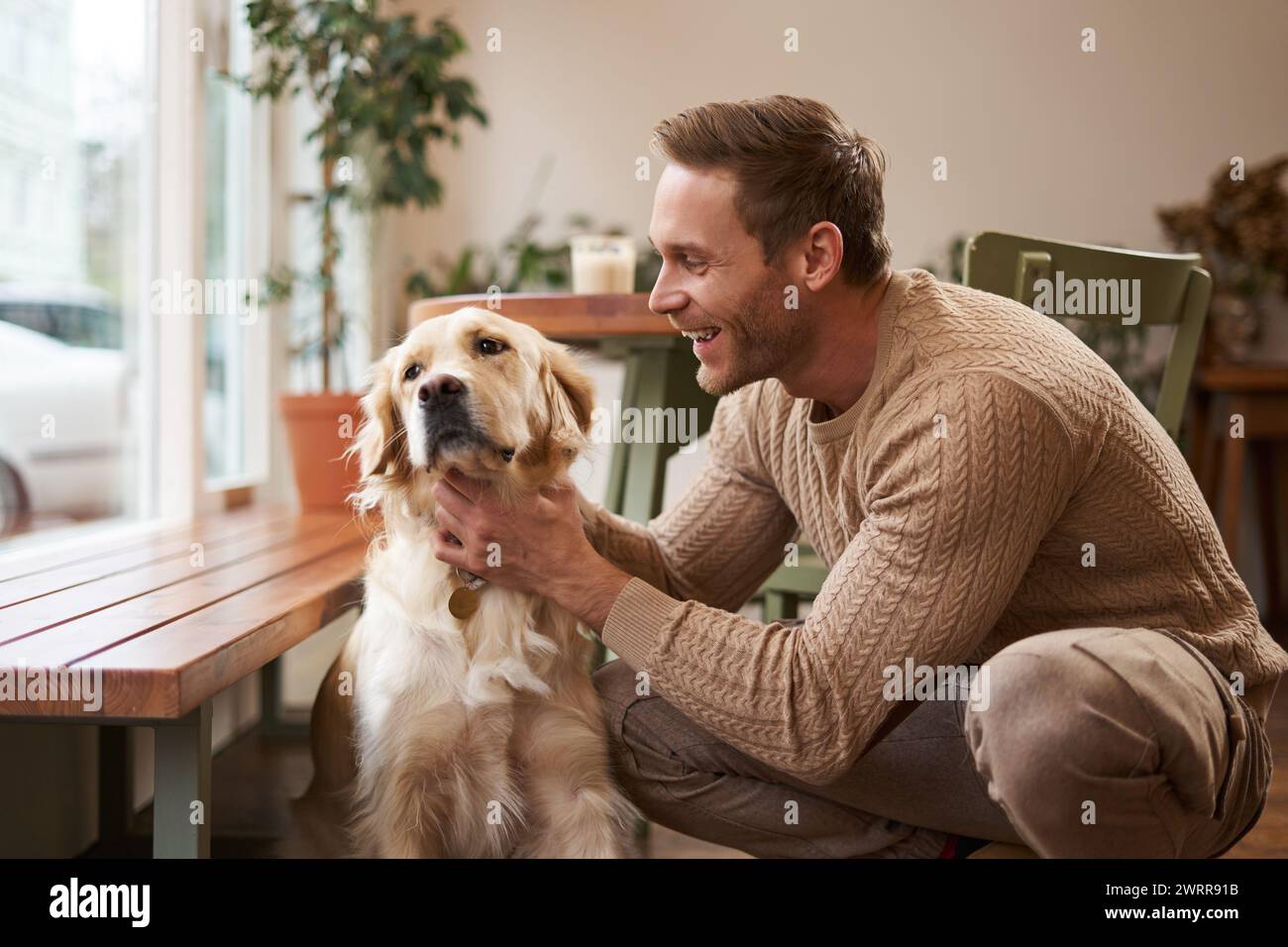 Portrait of happy smiling handsome man, pets his golden retriever and ...