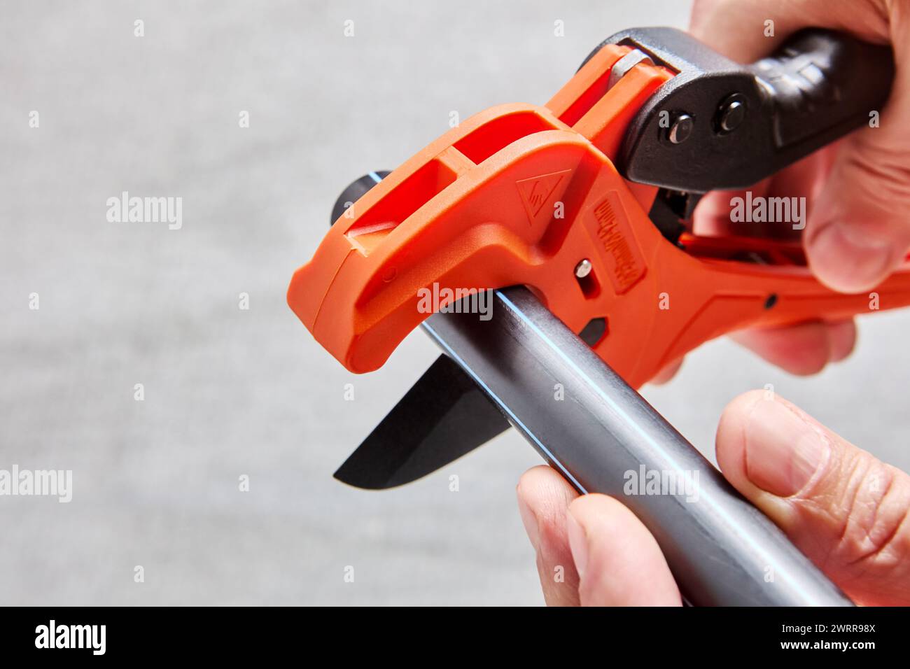 Cutting plastic pipe with ratchet cutter in shape of scissors, plumbers ...