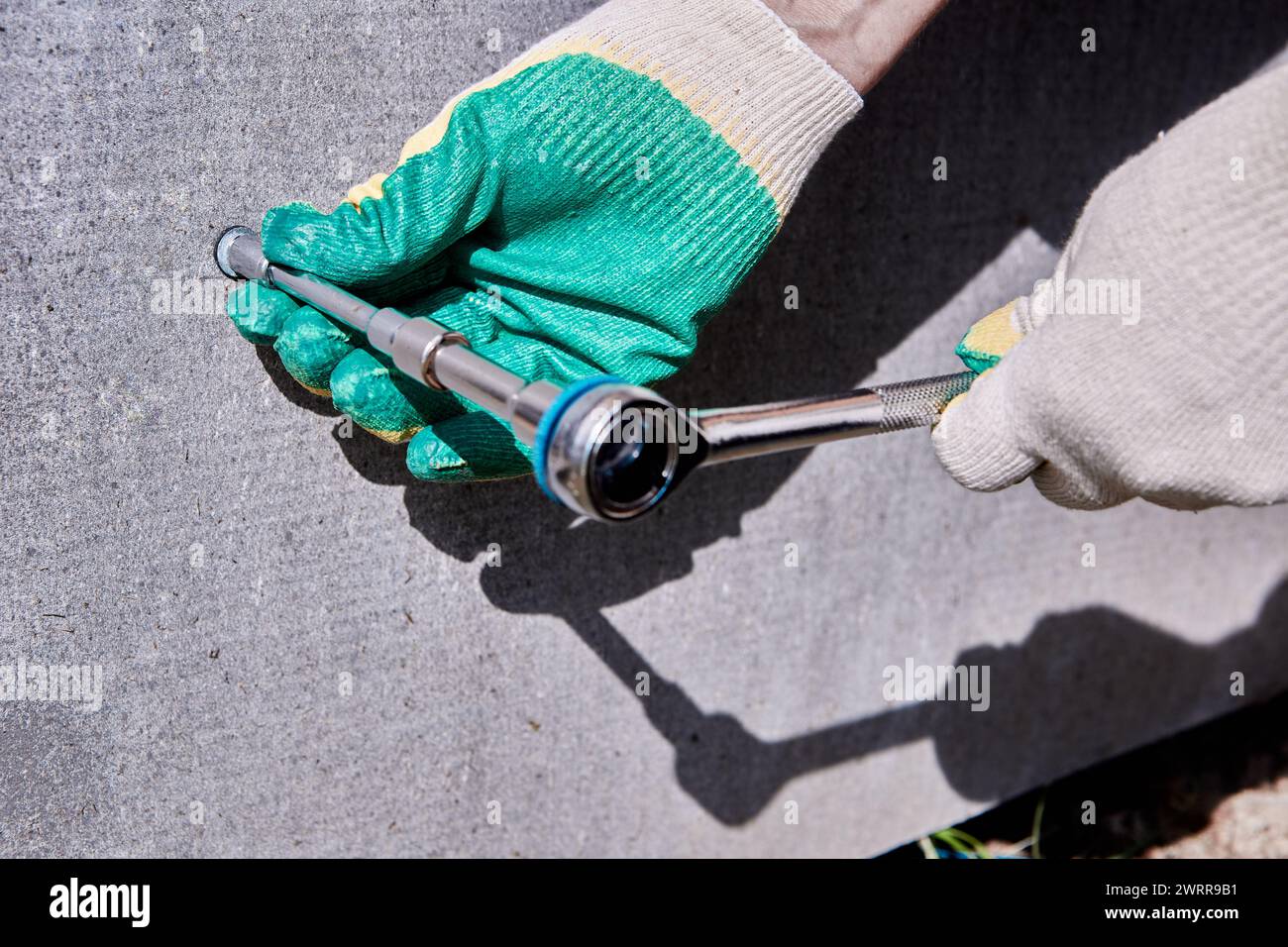 Finishing plinth on stilts with flat slate, worker uses socket wrench ...