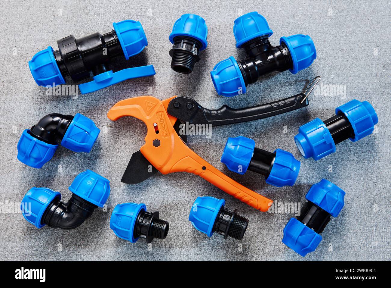 Set of PP compression pipe fittings are laid out on gray surface around ...