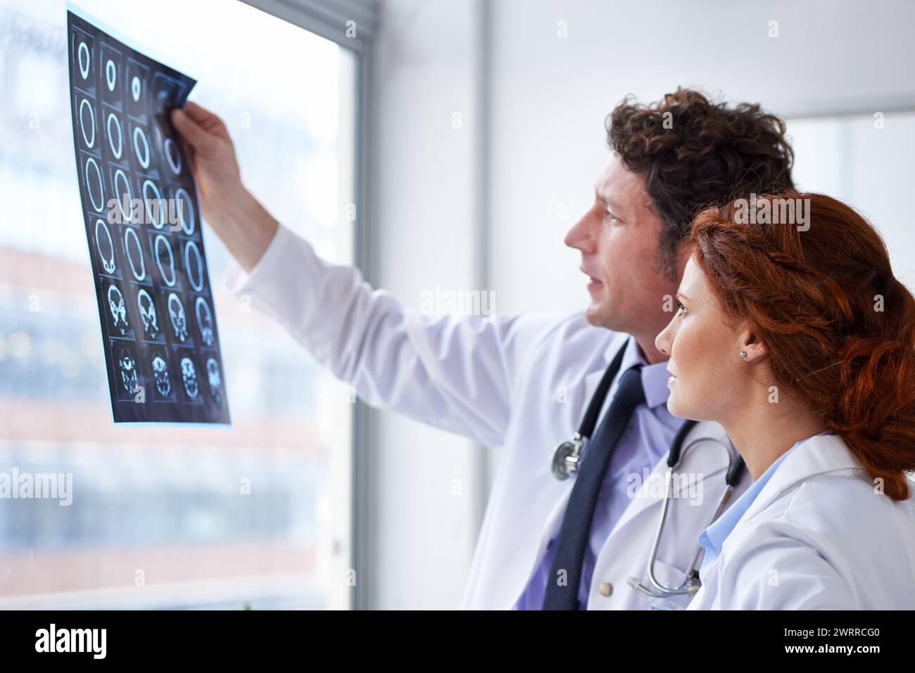 Doctors, brain scan and check results at hospital with teamwork, review and healthcare by window ...