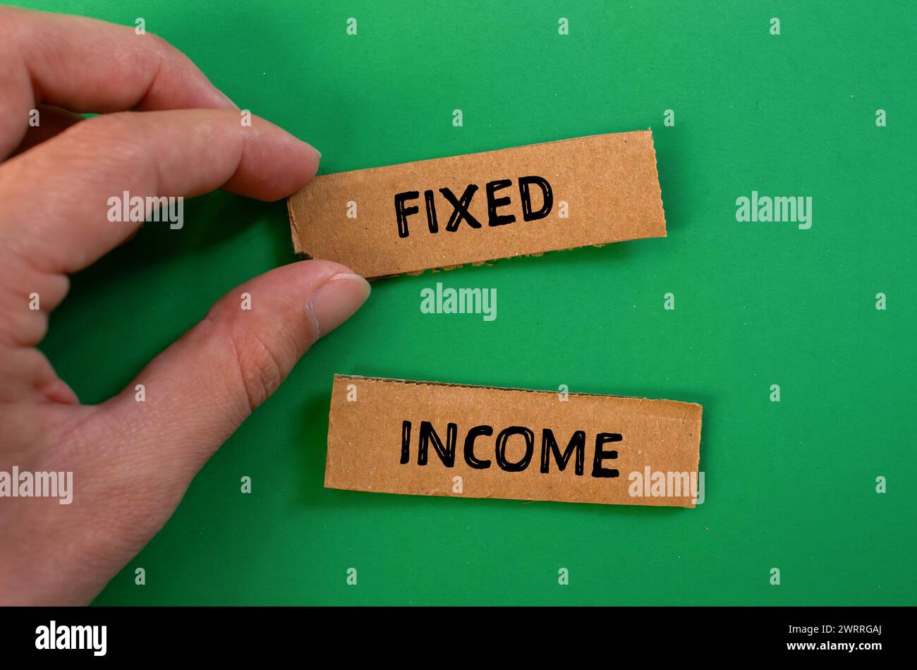 Fixed income words written on torn paper pieces with green background ...