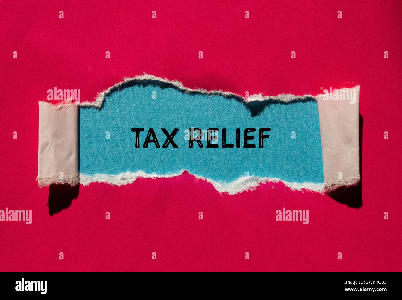 Tax relief words written on red torn paper with blue background ...
