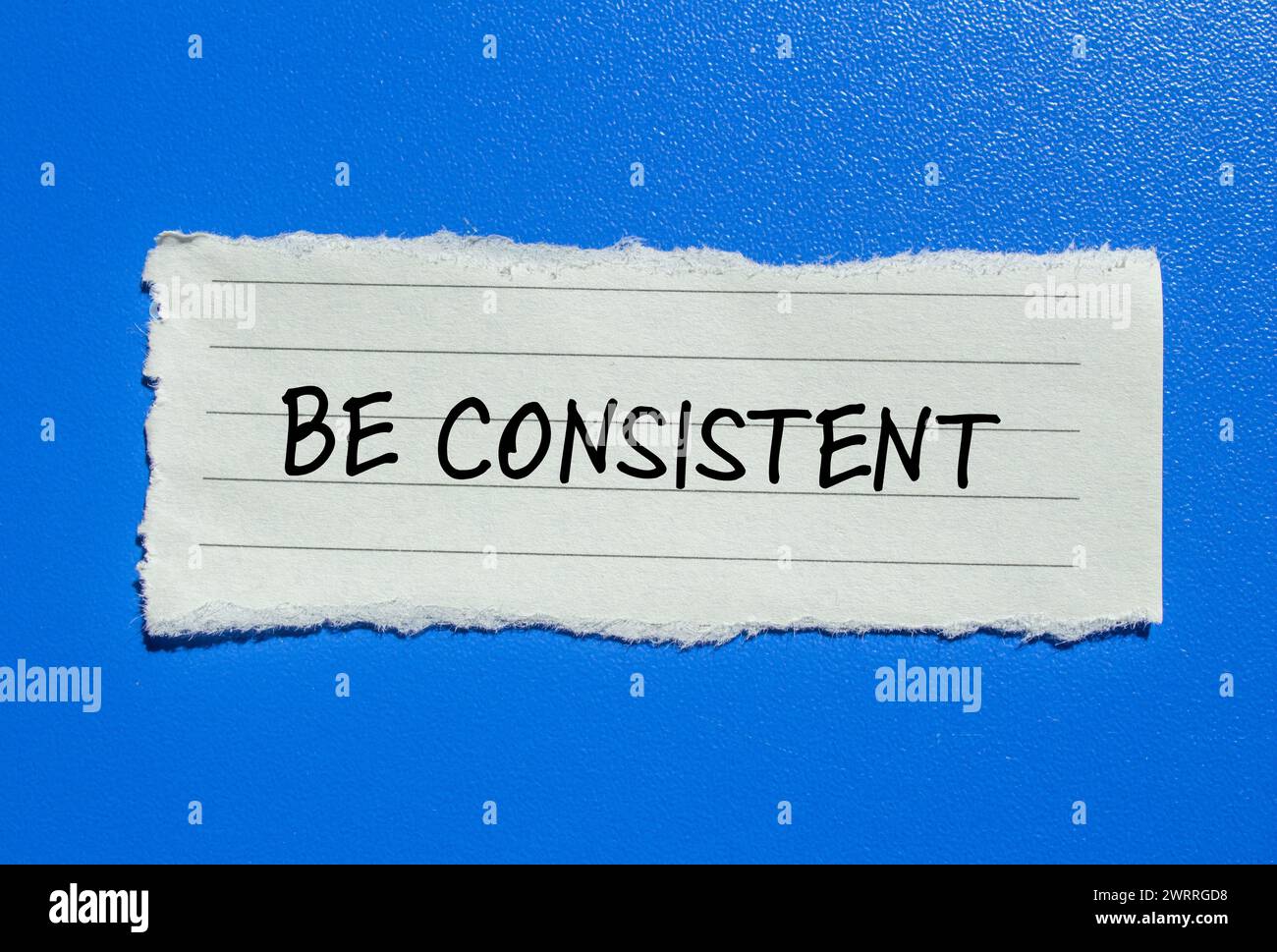 Be consistent words written on torn paper with blue background ...