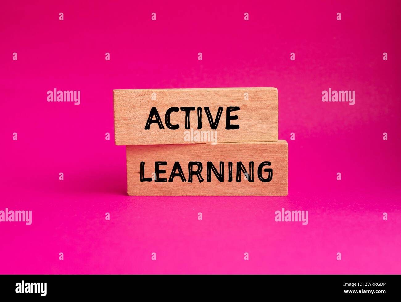 Active learning words written on wooden blocks with pink background ...