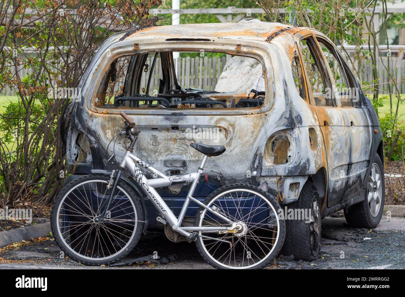 Bike leaning against burnt out car Stock Photo - Alamy