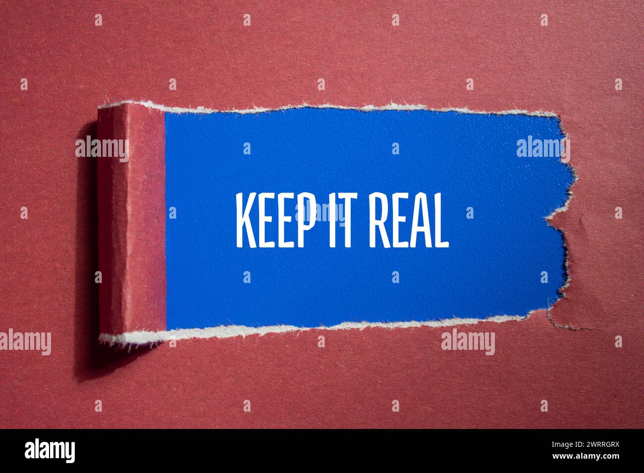 Keep it real words written on red torn paper with blue background ...