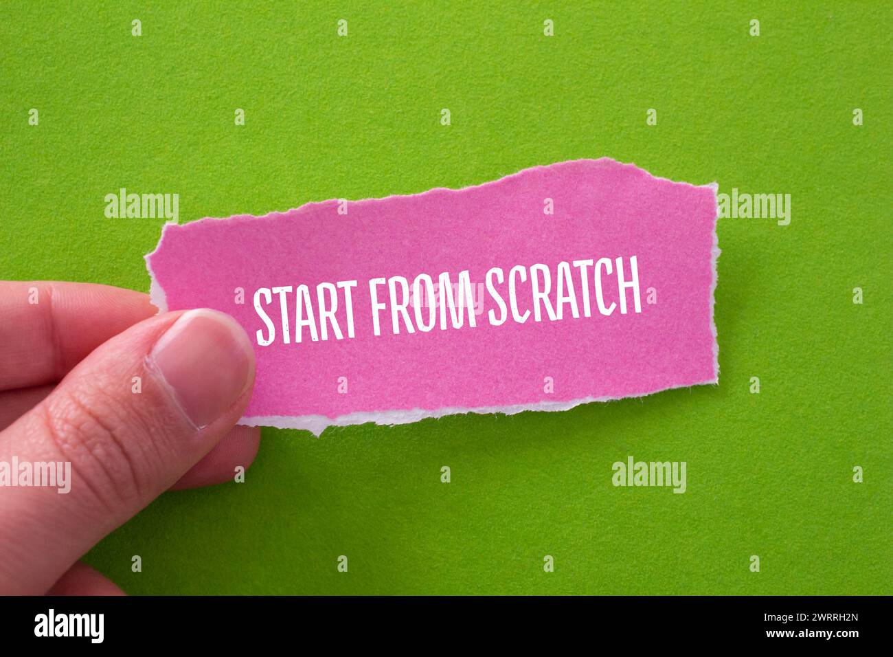 Start from scratch words written on pink torn paper with green background. Conceptual symbol ...
