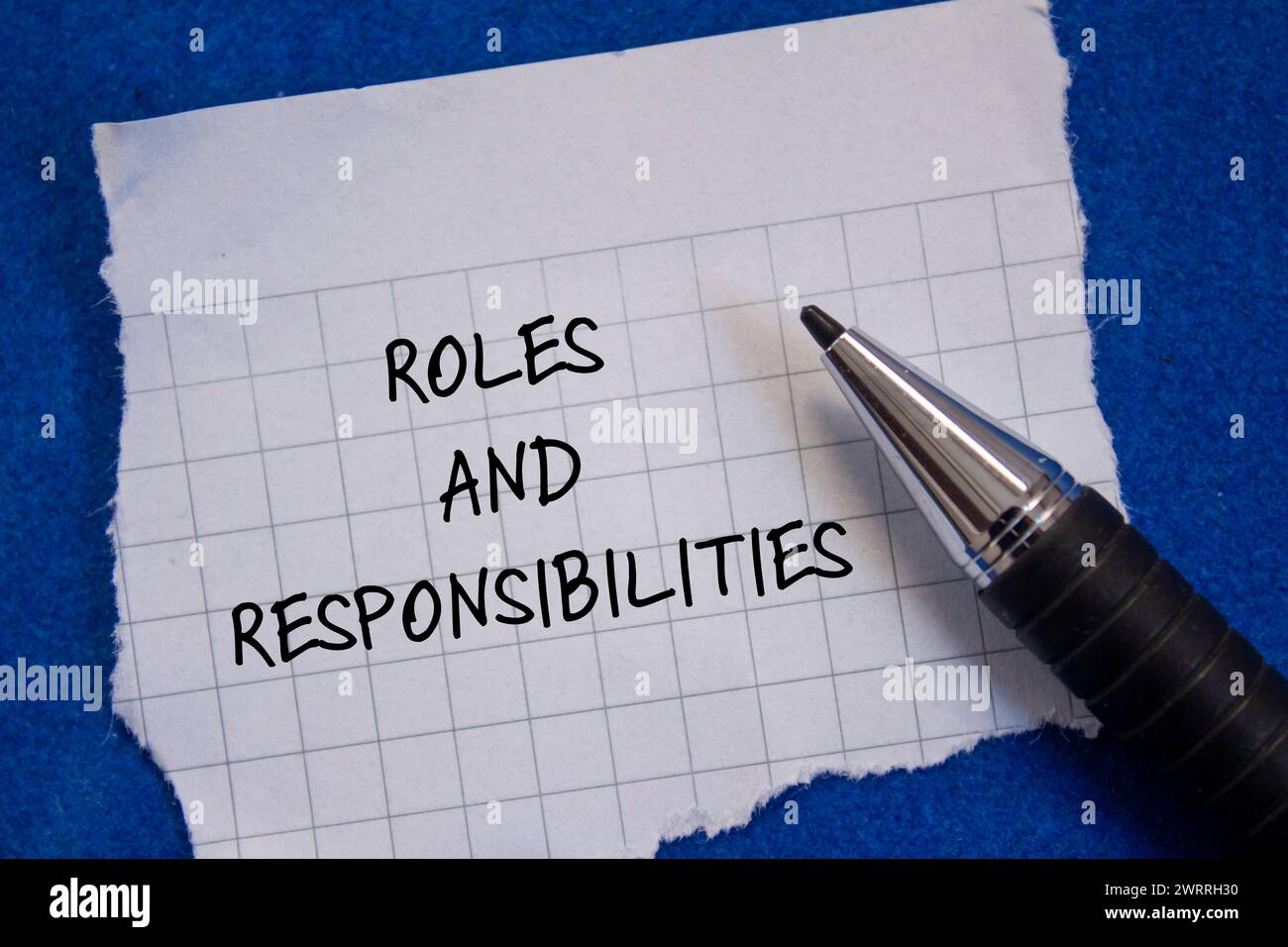 Roles and responsibilities words written on torn paper piece with blue ...