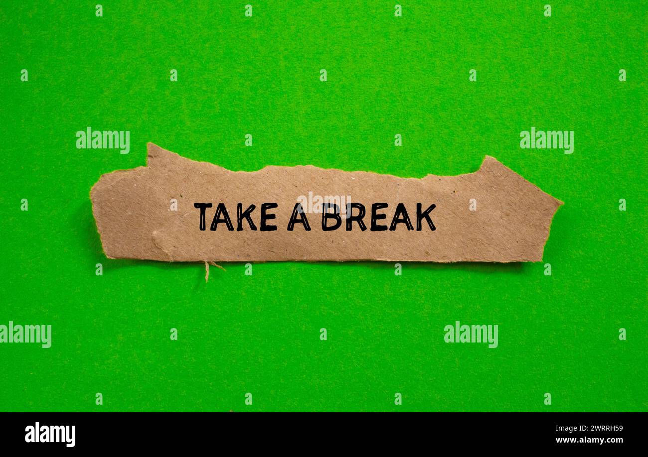 Take a break words written on torn paper piece with green background ...