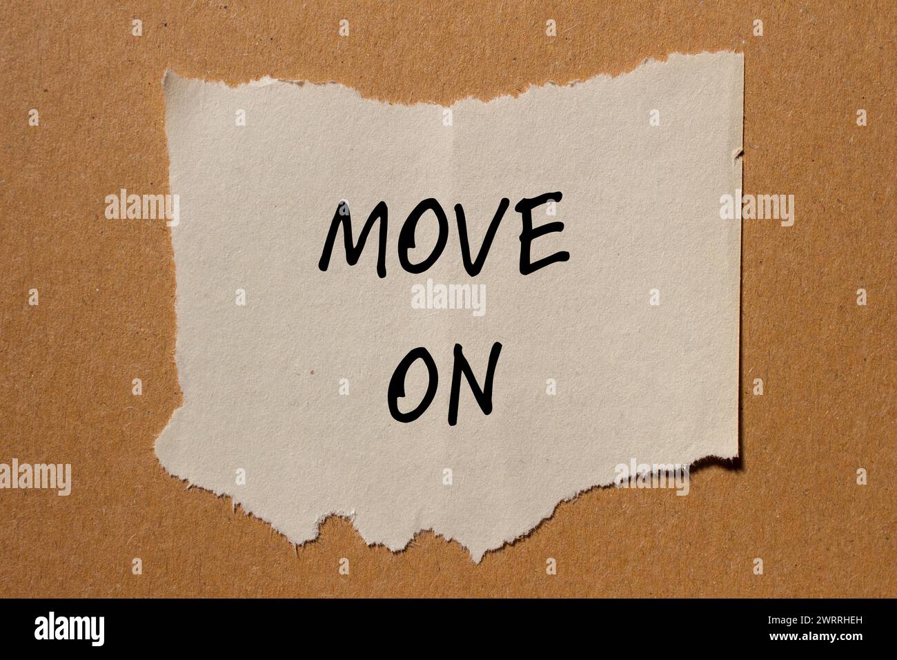 Move on words written on torn paper piece with brown background. Conceptual symbol. Copy space ...
