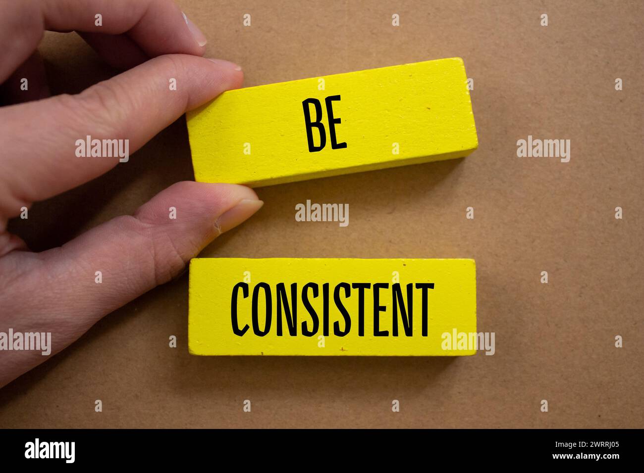 Be consistent words written on wooden blocks with brown background ...