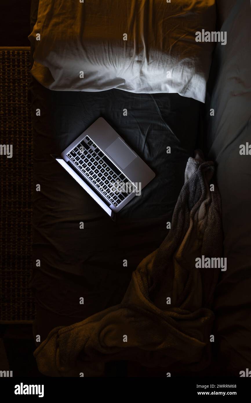 Laptop on the bed at night, light from the laptop screen, top view ...