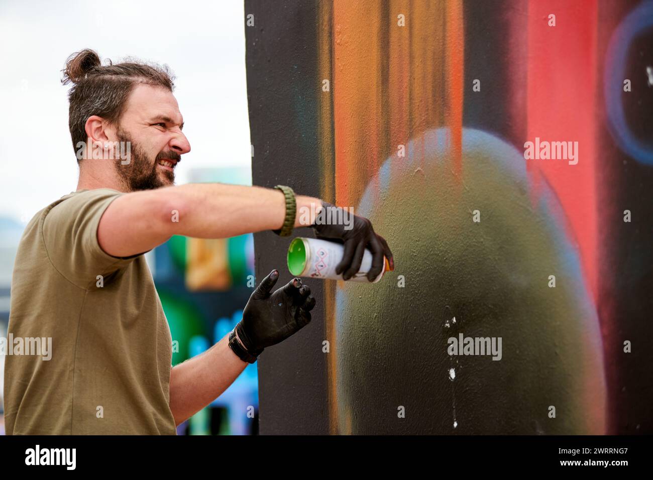 Attractive male artist is painting picture with paint spray can ...