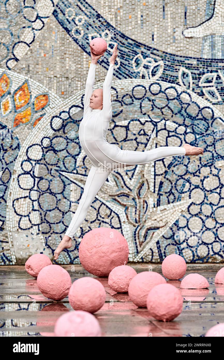 Young hairless girl ballerina with alopecia in white futuristic suit ...