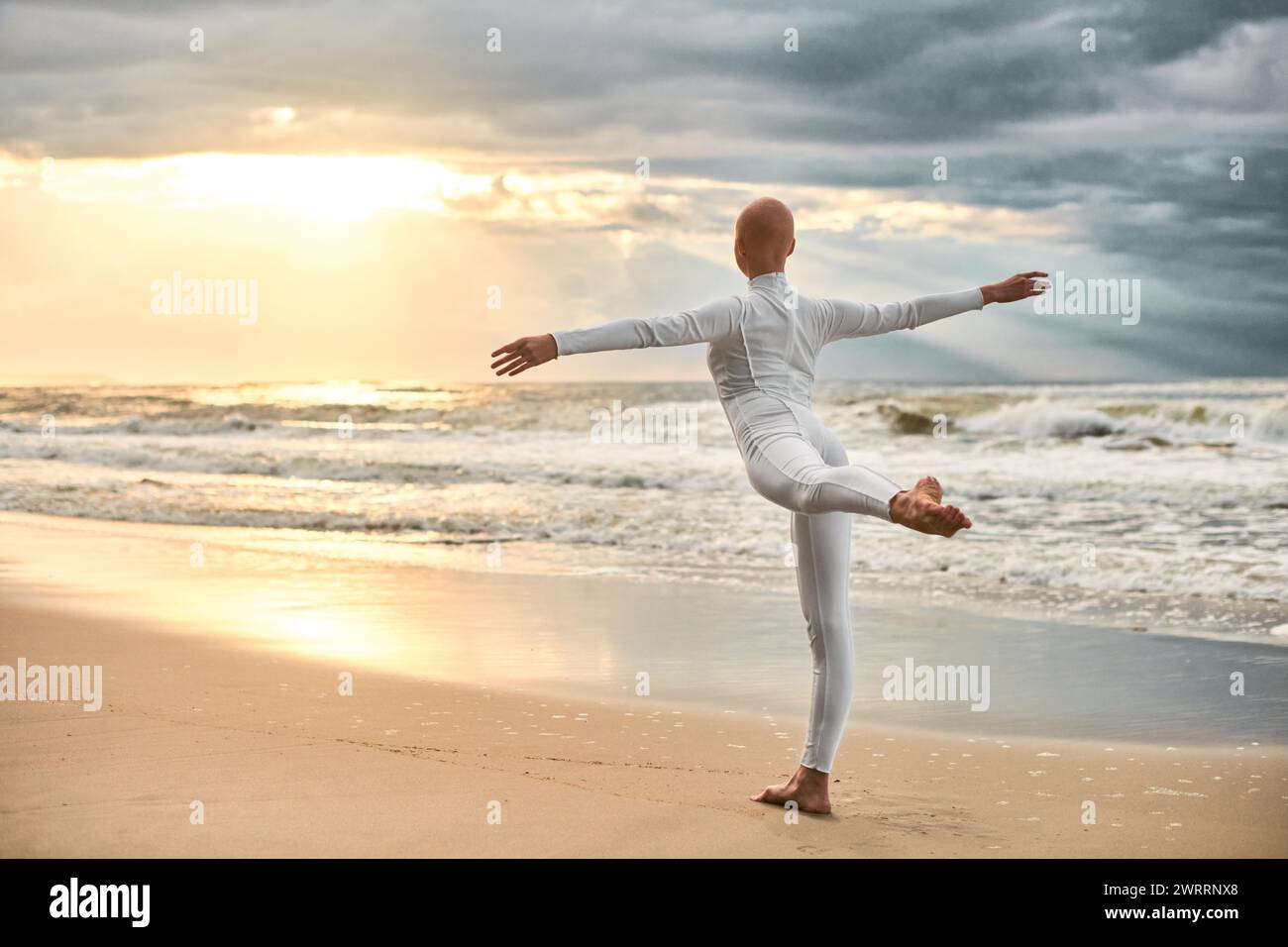 Young hairless ballerina with alopecia in white futuristic suit dancing ...