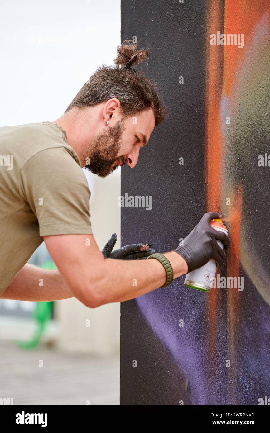 Attractive male artist is painting picture with paint spray can ...