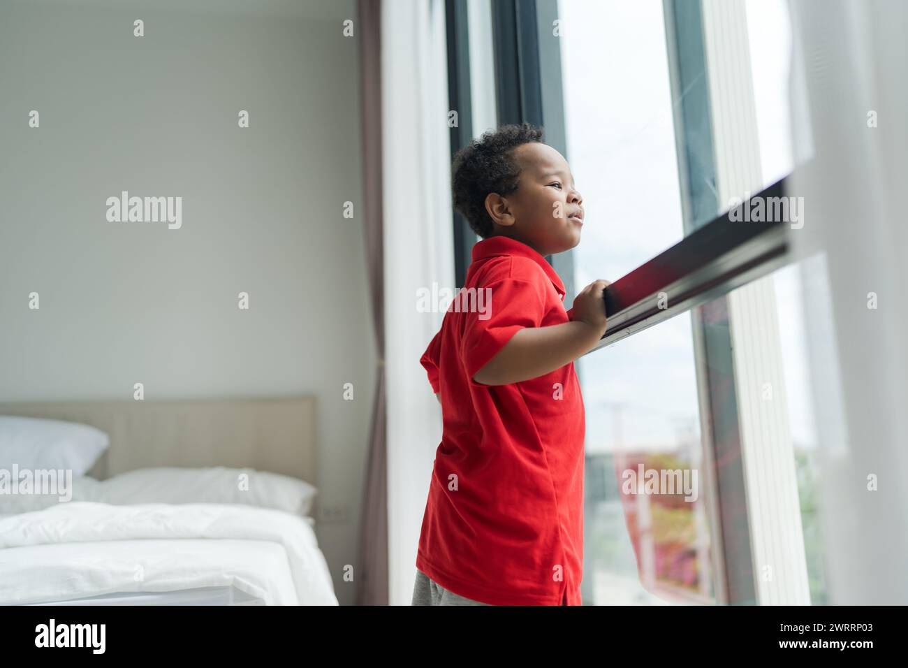 The little boy stood looking out the window on a clear day The little ...