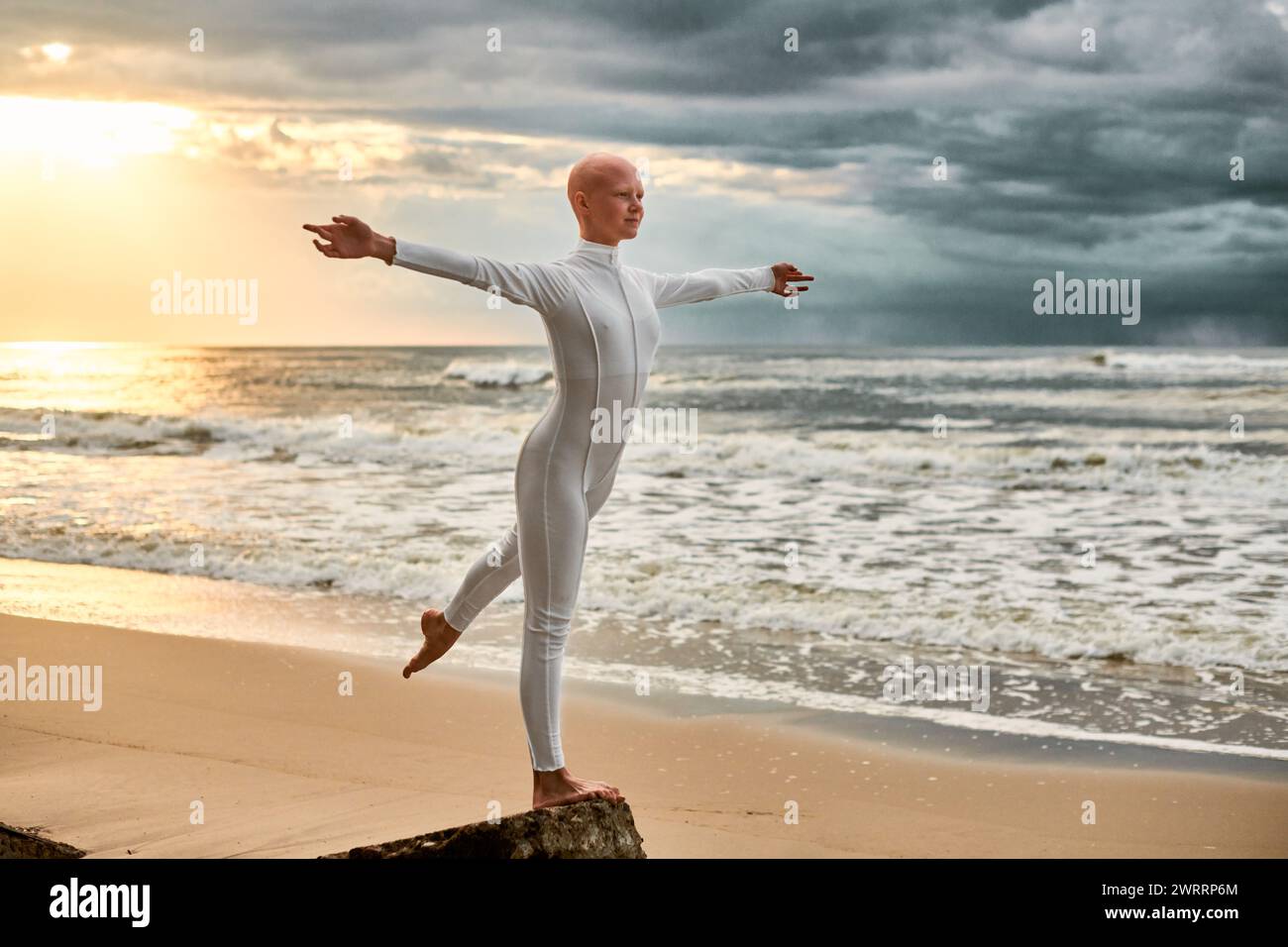 Young hairless ballerina with alopecia in white futuristic suit dancing ...