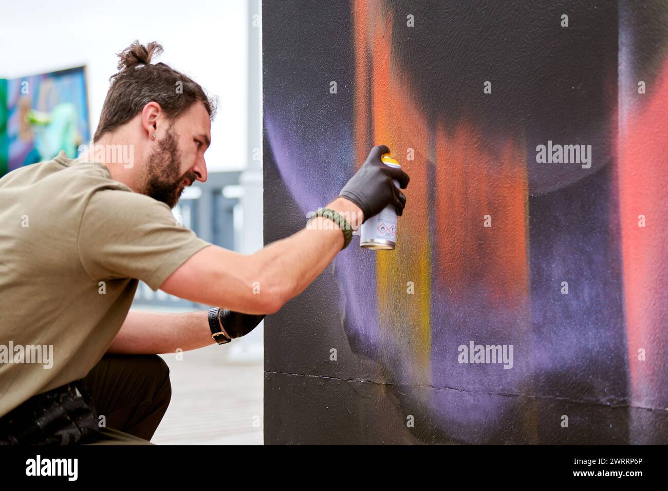 Attractive male artist is painting picture with paint spray can ...