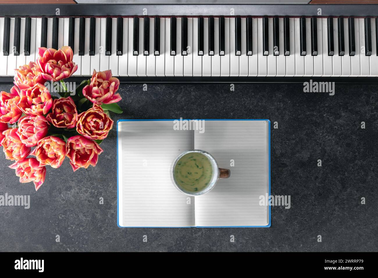 Piano, bouquet of spring flowers, notepad and cup of tea on a dark ...