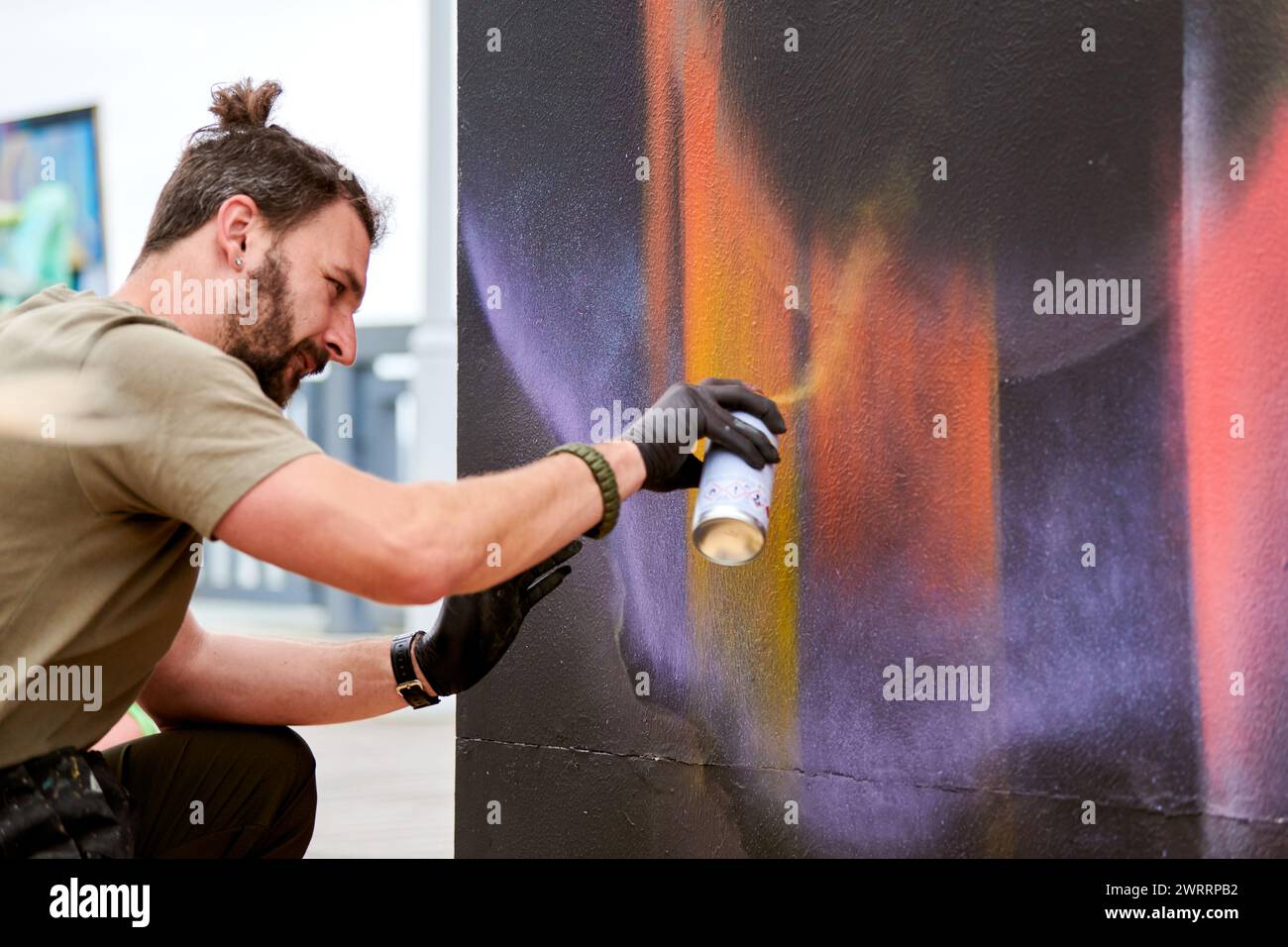 Attractive male artist is painting picture with paint spray can ...