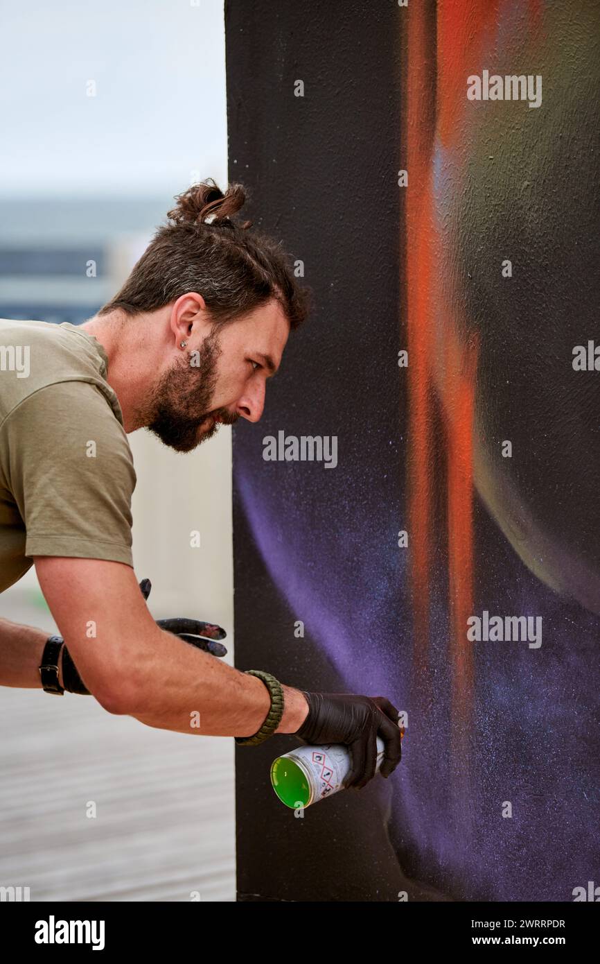 Attractive male artist is painting picture with paint spray can ...