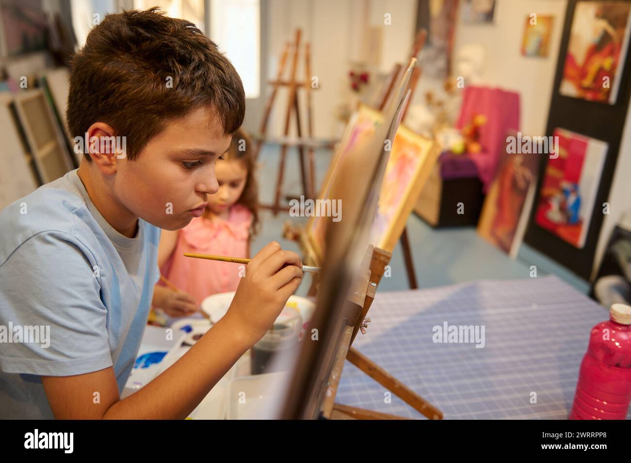 Caucasian handsome teenage school boy focused on painting on canvas in ...