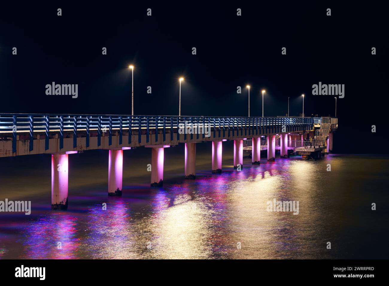 Sea pier adorned multicolored twinkling lights at night symbolizes ...