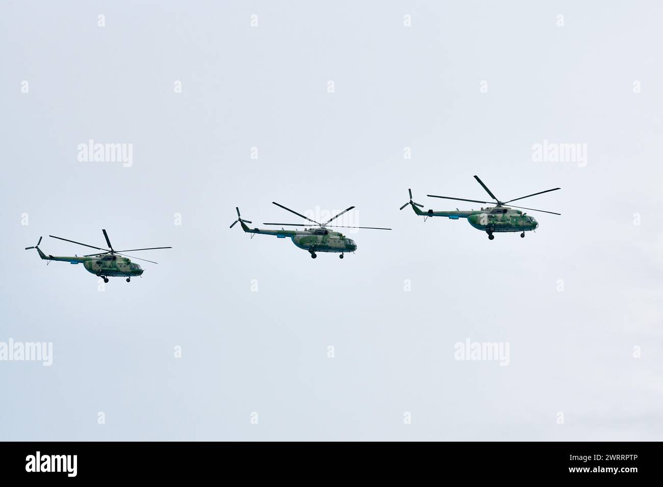 Three Russian military helicopters armed with missiles flies in blue ...