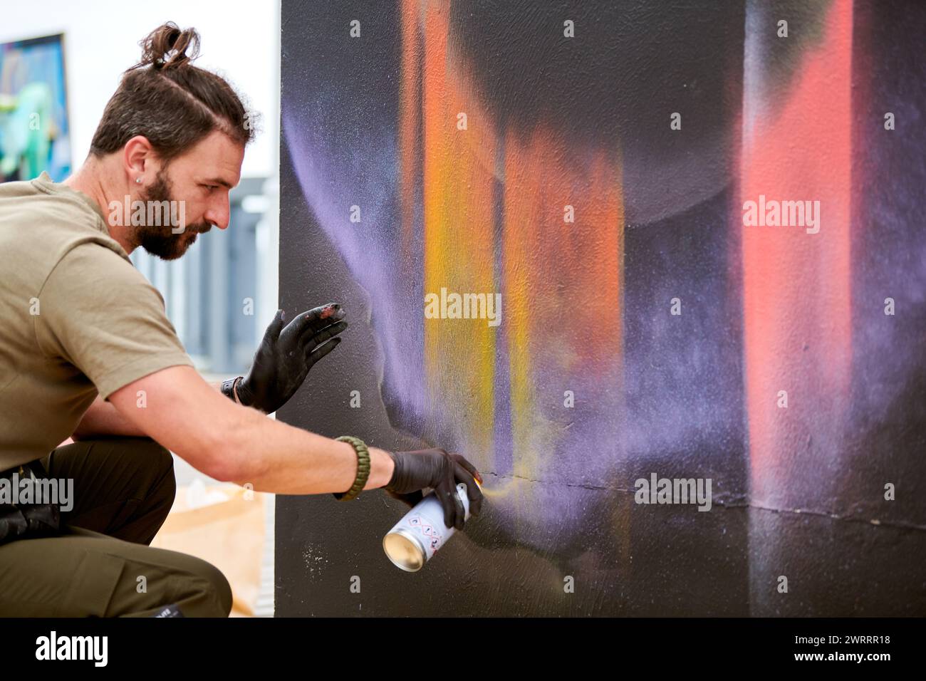 Attractive male artist is painting picture with paint spray can ...