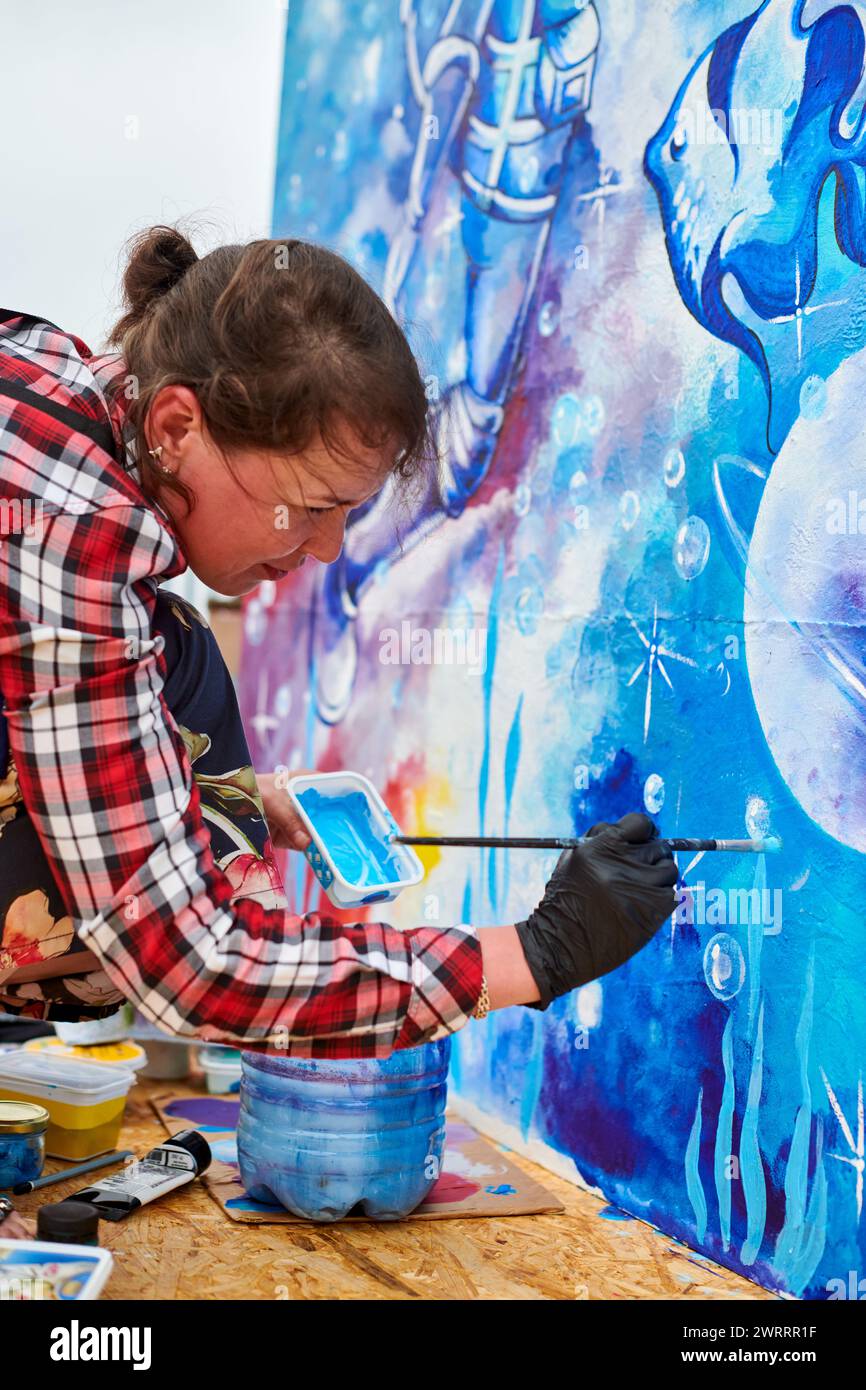 Female painter draws picture with paintbrush on canvas for outdoor ...