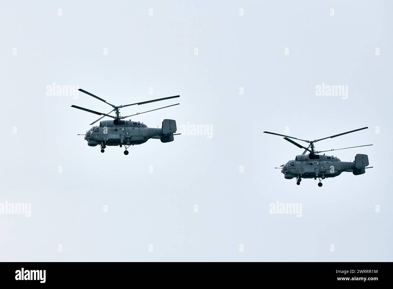 Two Russian military helicopters armed with missiles flies in blue sky ...