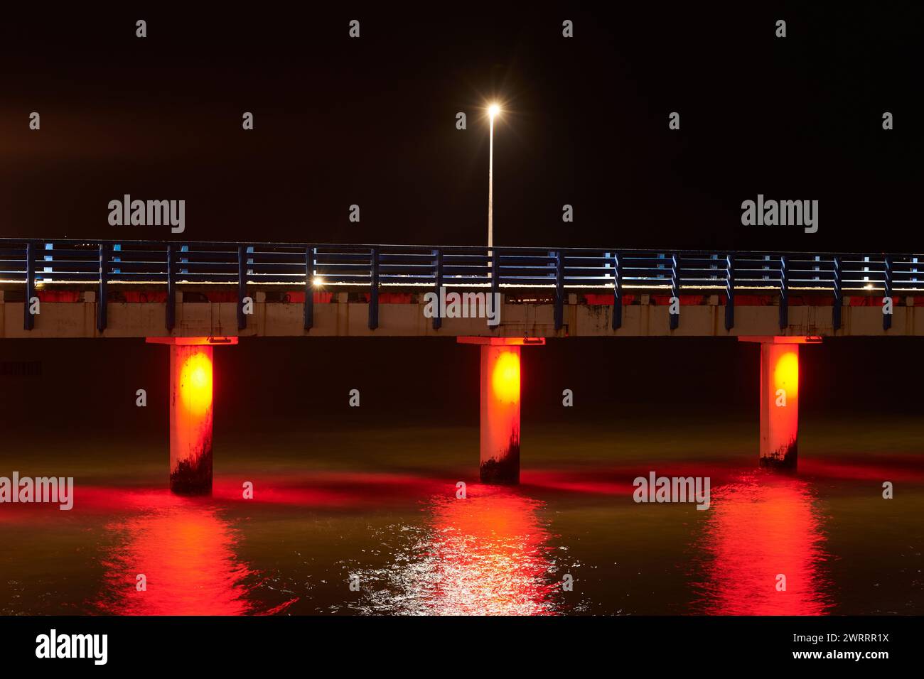 Sea pier adorned multicolored twinkling lights at night symbolizes ...