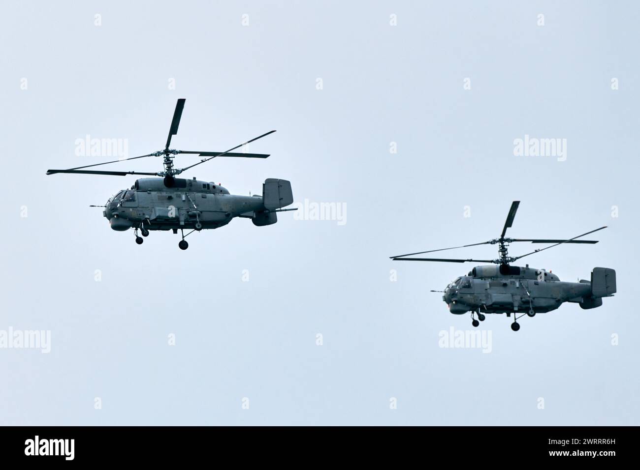 Two Russian military helicopters armed with missiles flies in blue sky ...