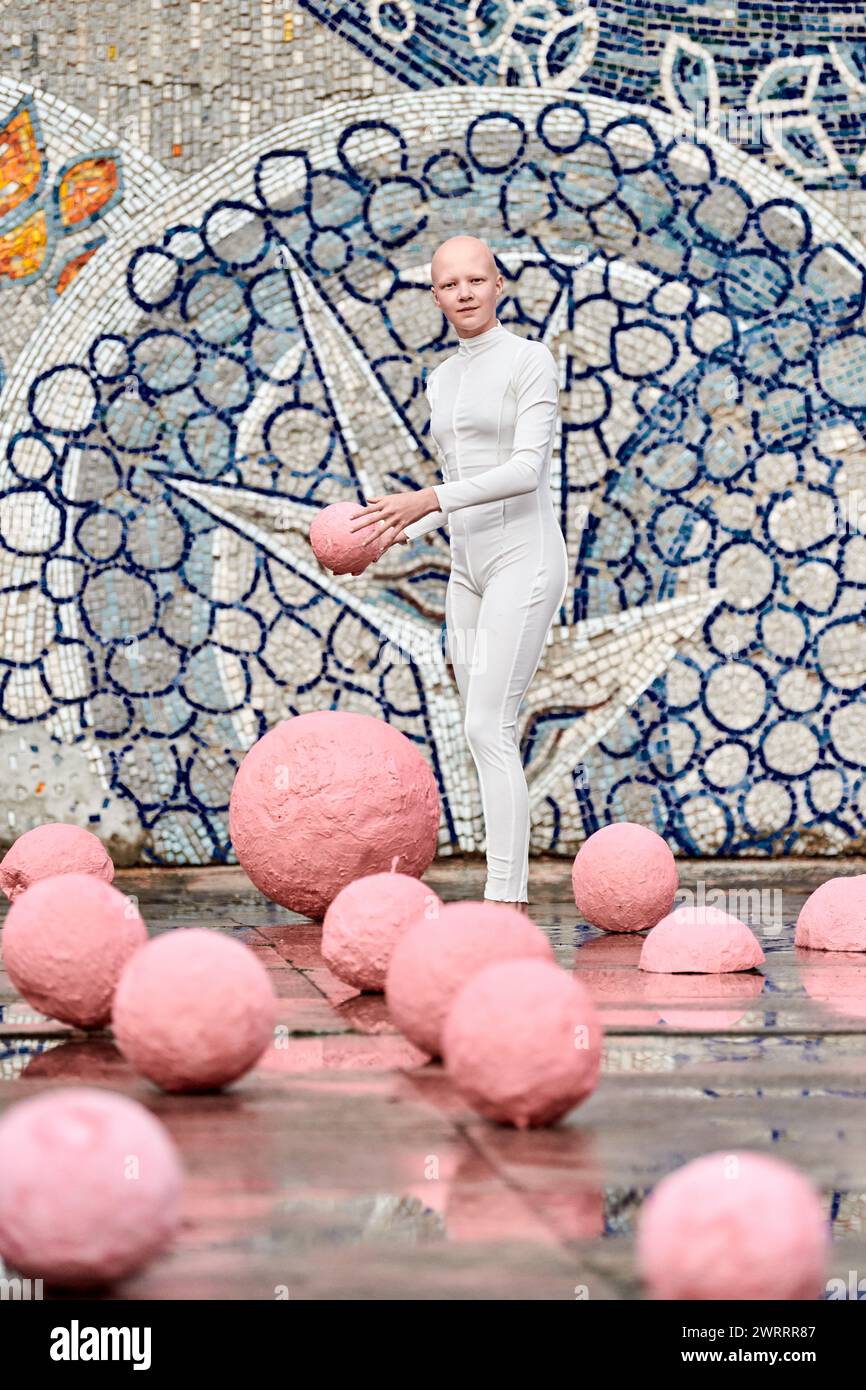 Young hairless girl ballerina with alopecia in white futuristic suit ...