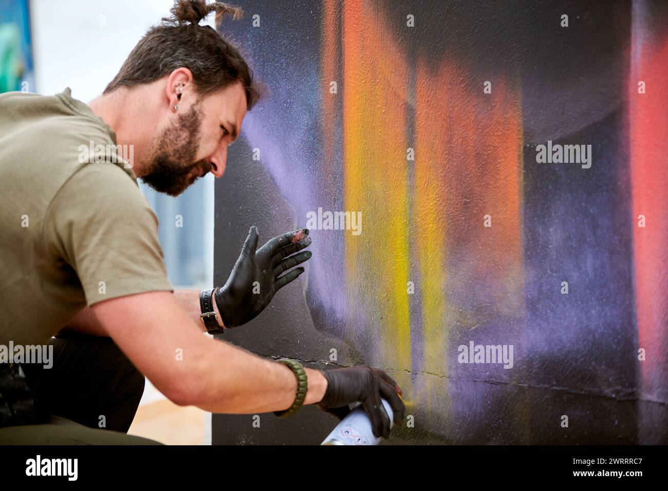 Attractive male artist is painting picture with paint spray can ...