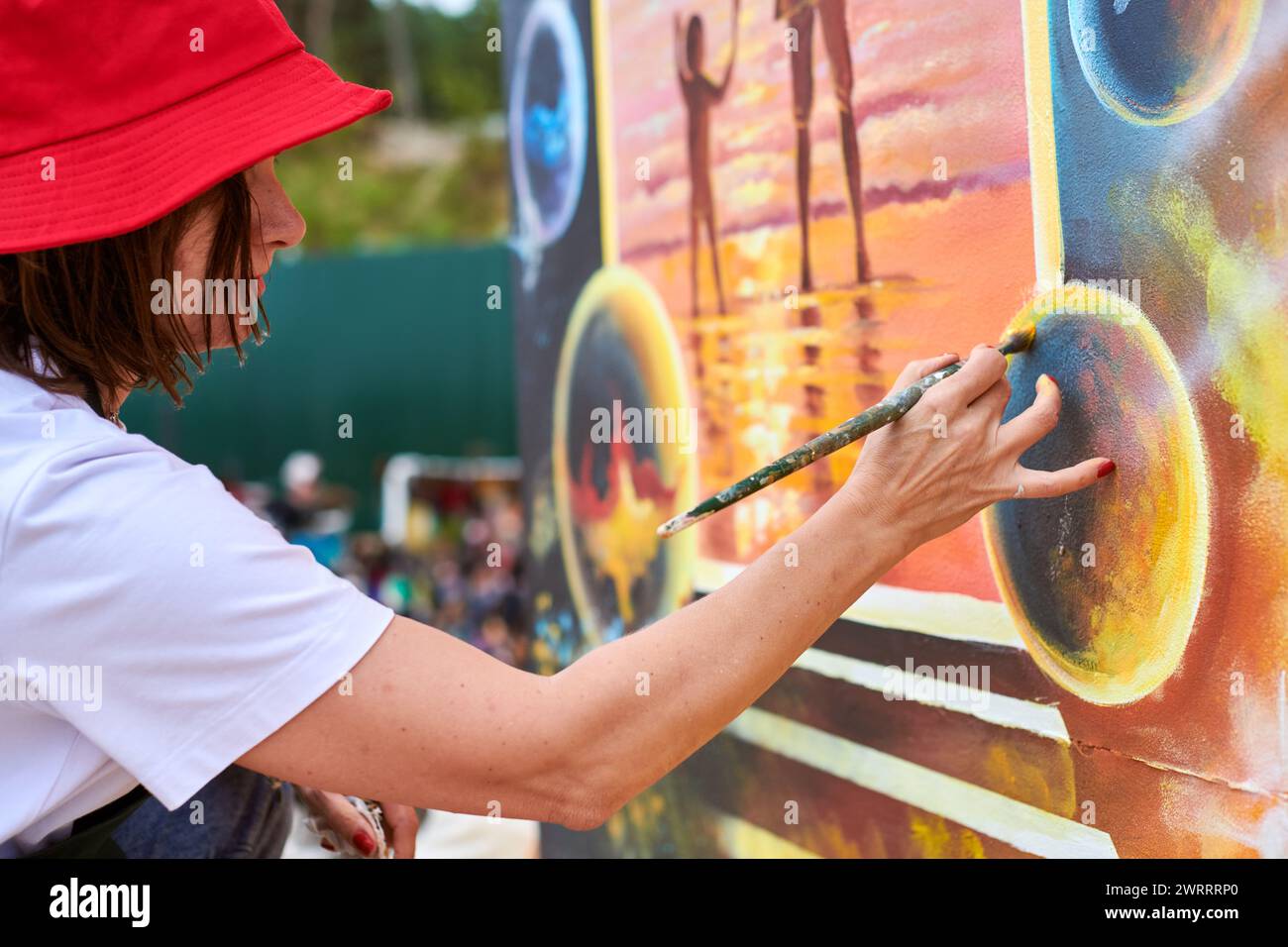 Female painter in red hat draws picture with paintbrush on canvas for ...